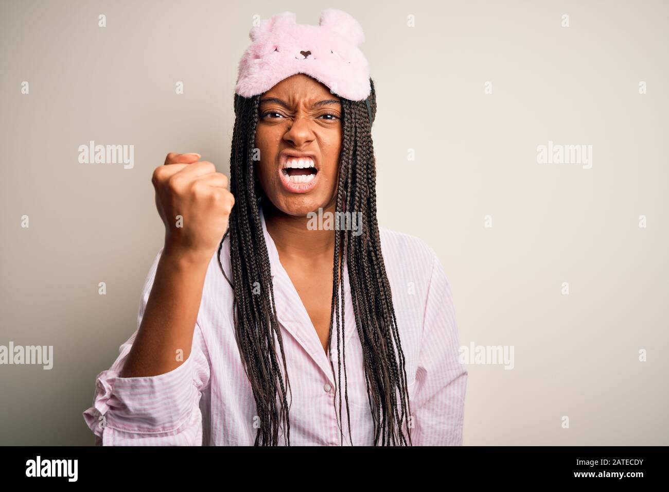 Young african american woman wearing pink pajama and sleep mask over ...