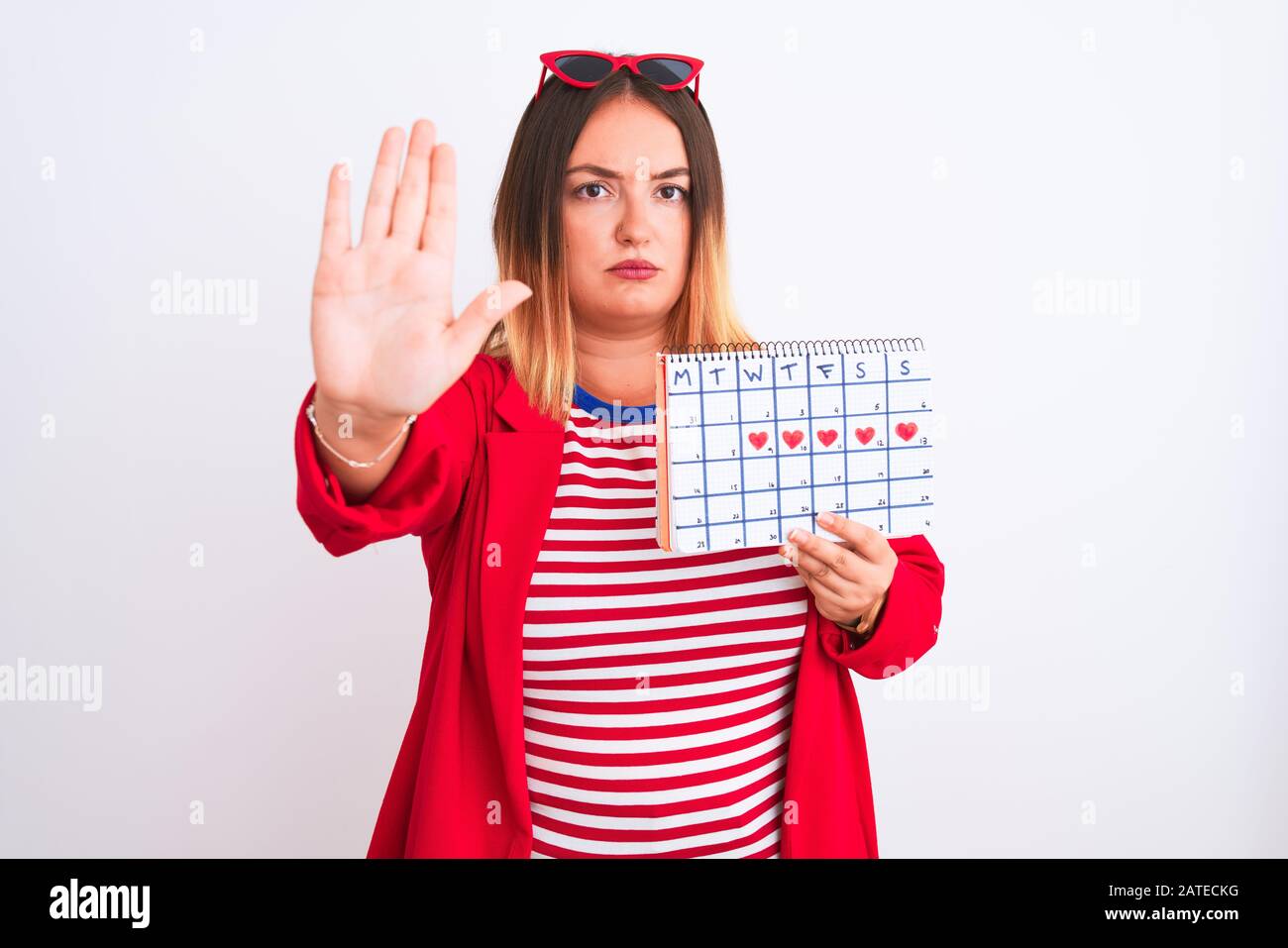 Young beautiful woman holding period calendar standing over isolated ...