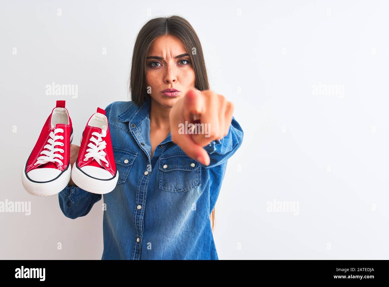 Young beautiful woman holding casual sneakers standing over isolated ...