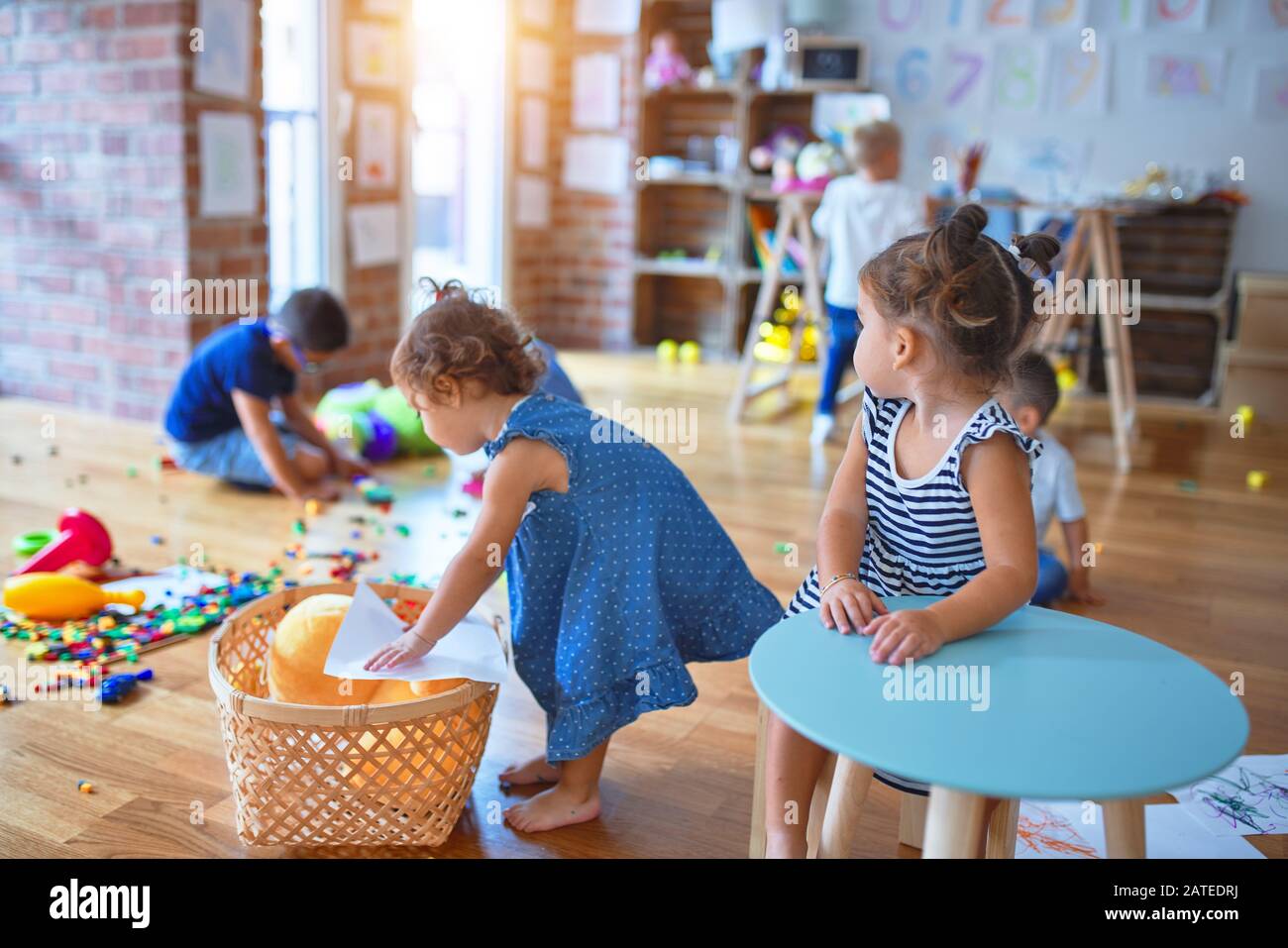 Adorable group of toddlers playing around lots of toys at kindergarten ...