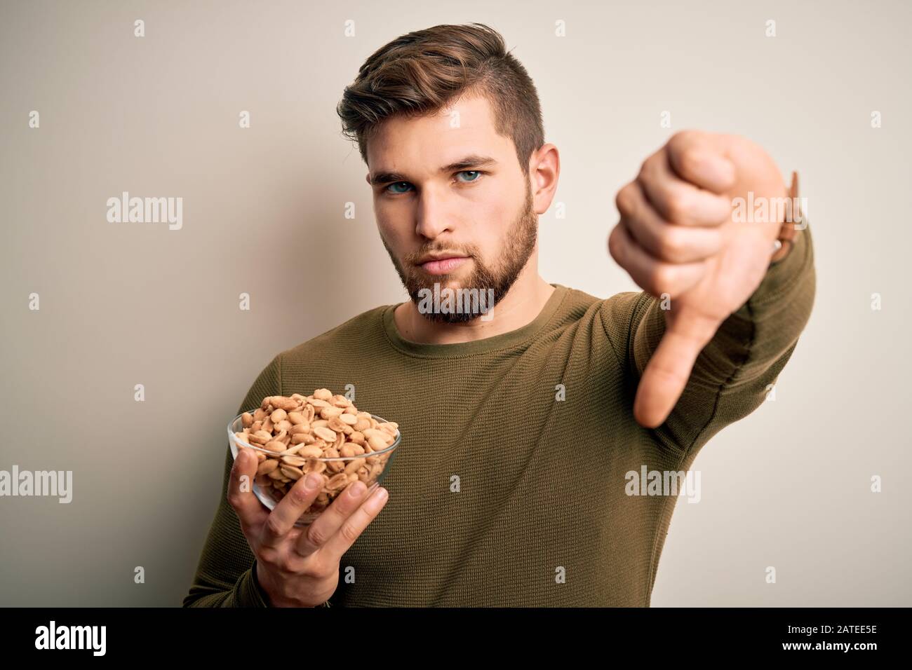 Young blond man with beard and blue eyes holding bowl with healthy ...