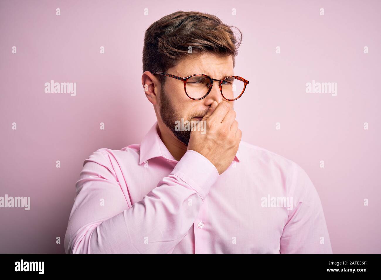 Young handsome blond man with beard and blue eyes wearing pink shirt ...