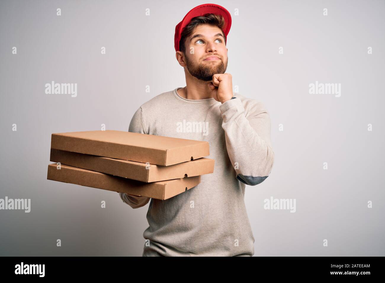 Young blond delivery man with beard and blue eyes holding cardboards of ...