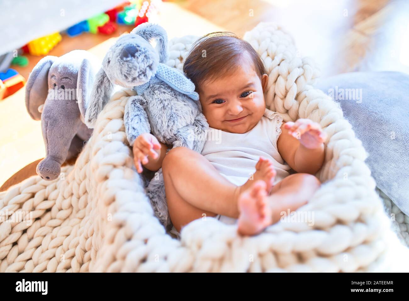 Beautiful infant happy at kindergarten around colorful toys lying ...