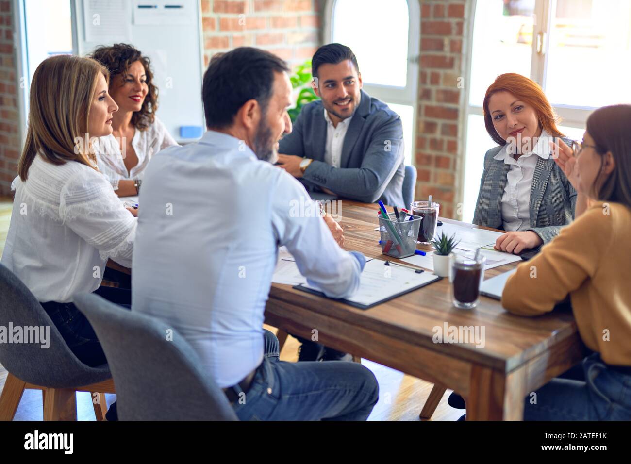 Group of business workers working together. Sitting on desk speaking at ...