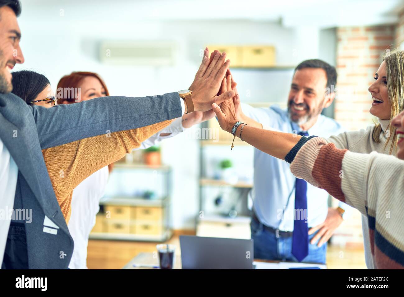 Group of business workers standing with hands together highing five at ...