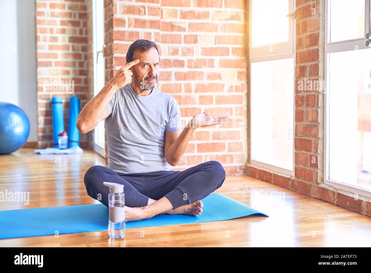 Middle age handsome sportman sitting on mat doing stretching yoga ...
