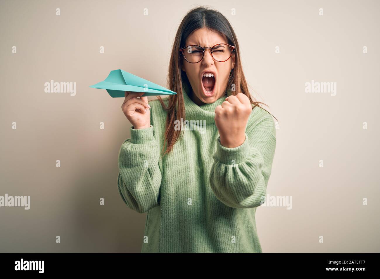 Young beautiful woman holding airplane of paper standing over isolated ...