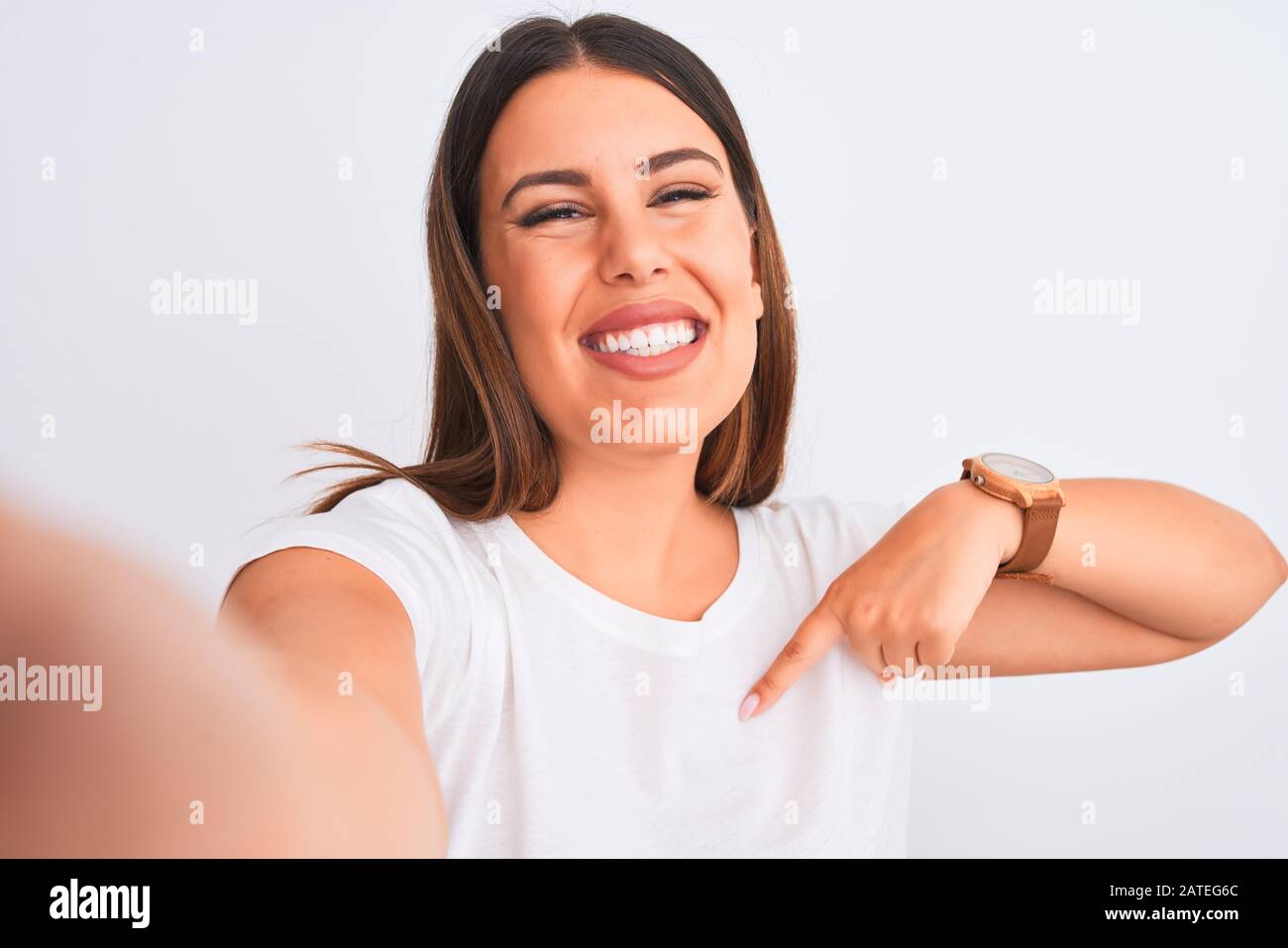 Beautiful young woman taking a selfie photo using smartphone over white ...