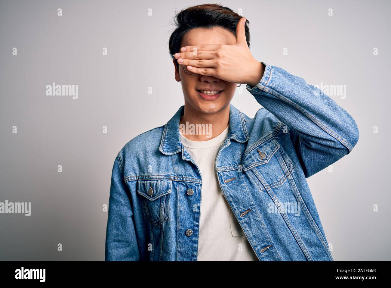 Young handsome chinese man wearing denim jacket and glasses over white ...