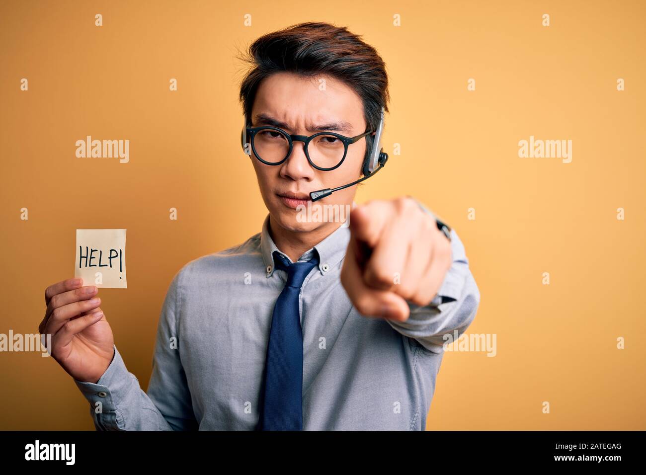 Young handsome chinese call center agent man overworked using headset ...