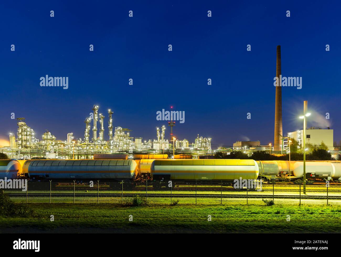 Industrial trains in front of refinery distillation towers with night ...