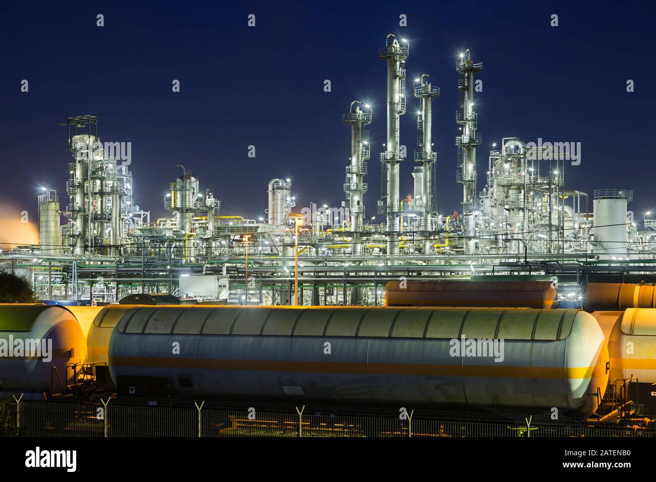 Industrial trains in front of refinery distillation towers with night ...