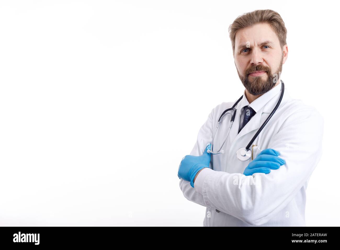 Cheerful doctor in white scrubs and medical gloves posing, arms crossed ...