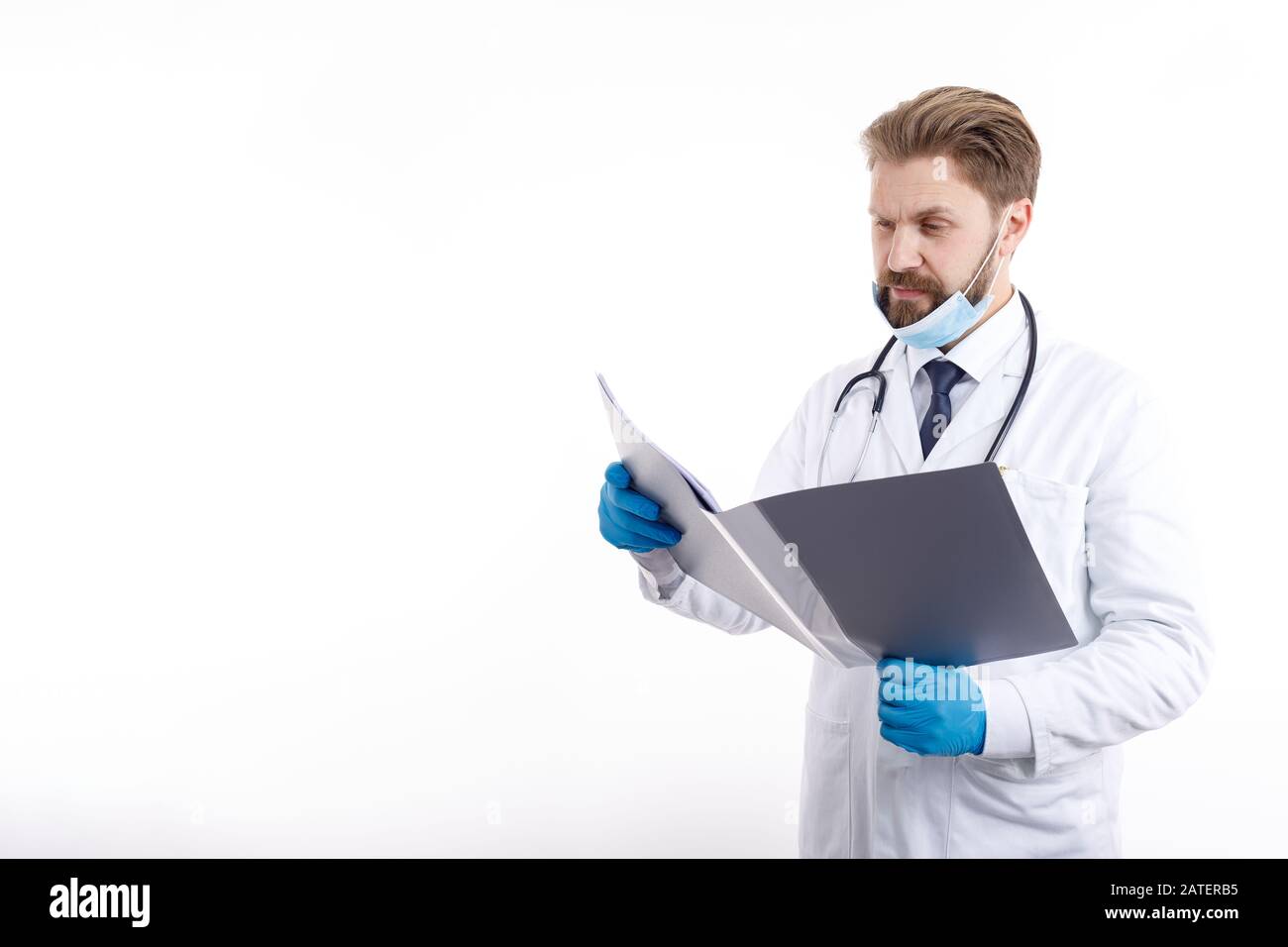 Bearded doctor in white scrubs and medical gloves exploring medical ...