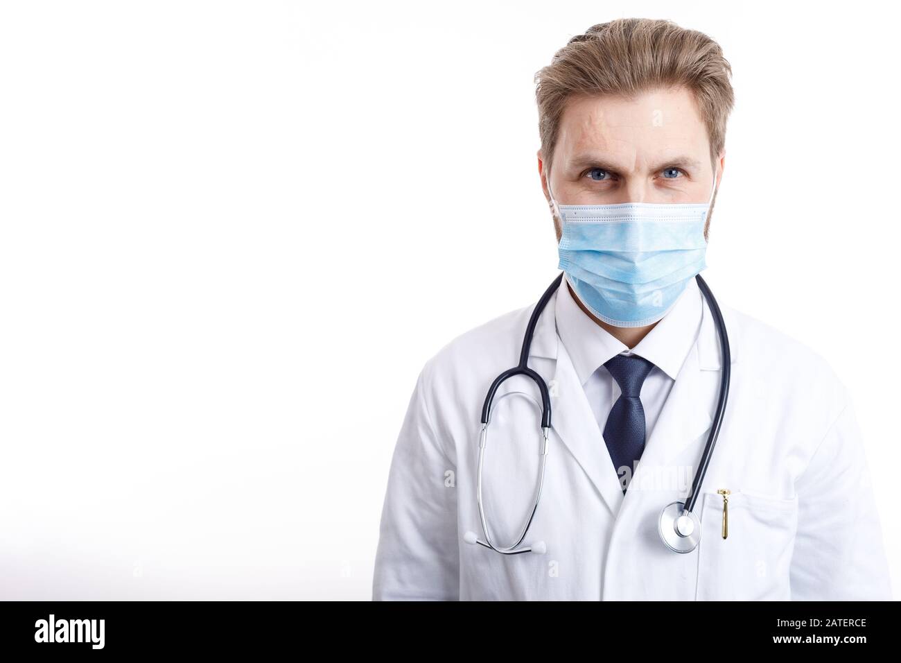 Concentrated doctor in white smock and medical mask giving a gaze ...