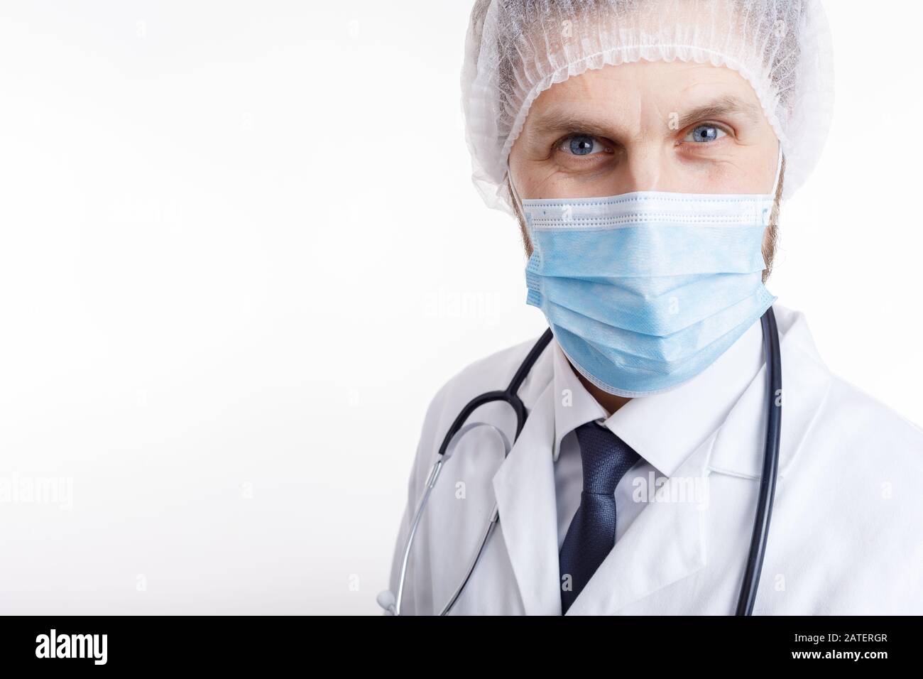 Close-up of male doctor in white smock, mask and medical cap with ...