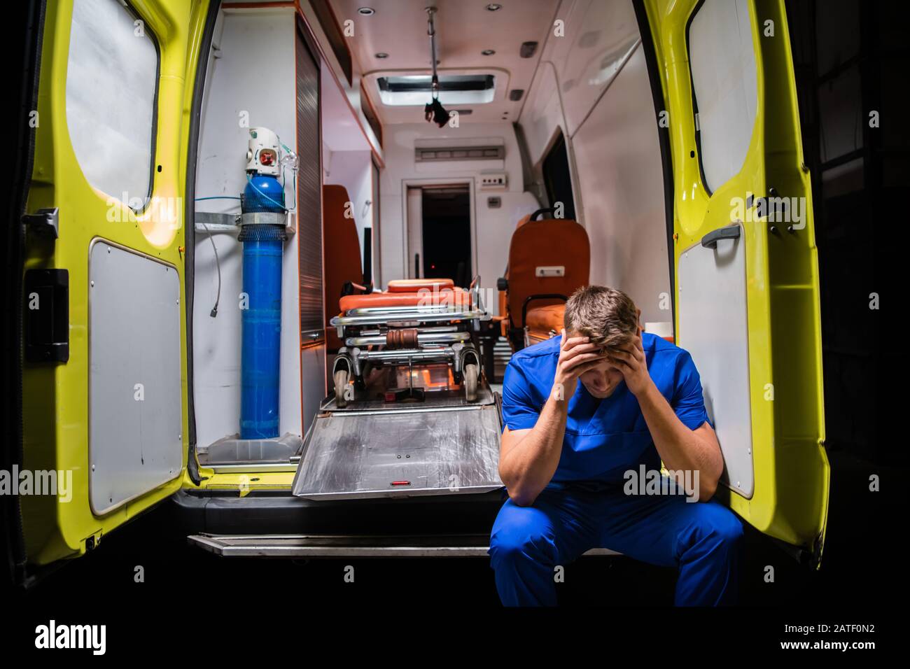 Confused corpsman in blue uniform sit on the ambulance car at night ...