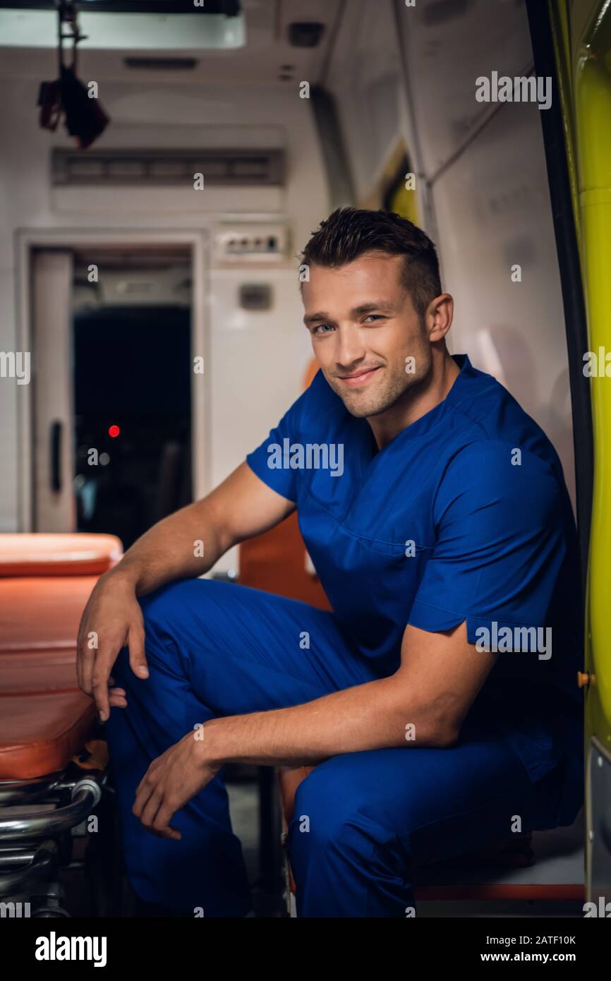 Smiling corpsman in blue medical uniform sits and squints in the ...