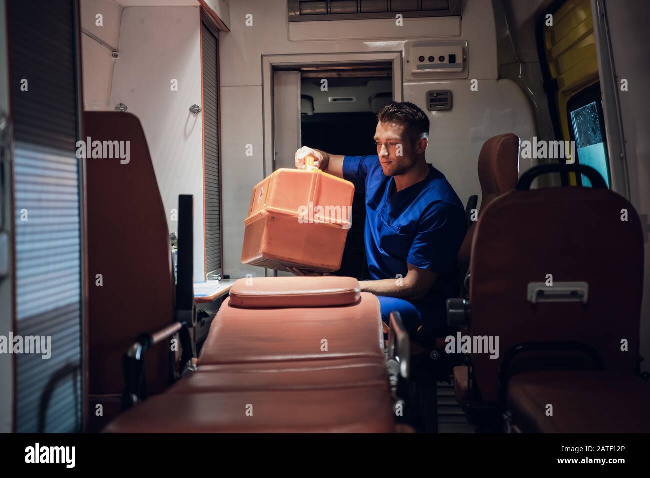 Corpsman in blue medical uniform sits in the ambulance car and packs ...