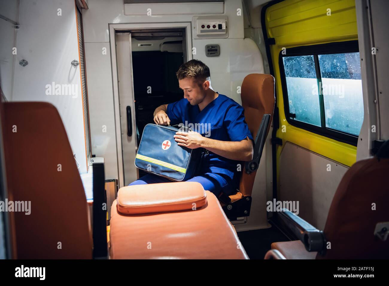 Corpsman in medical uniform sits in the ambulance car and holds medical ...