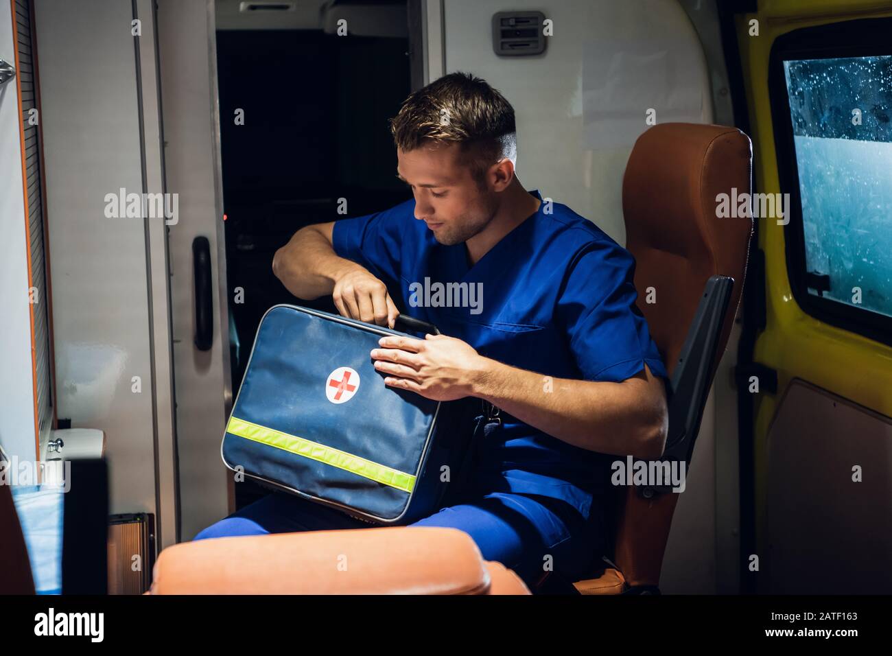 Corpsman in blue uniform sits in the ambulance car and packs medical ...