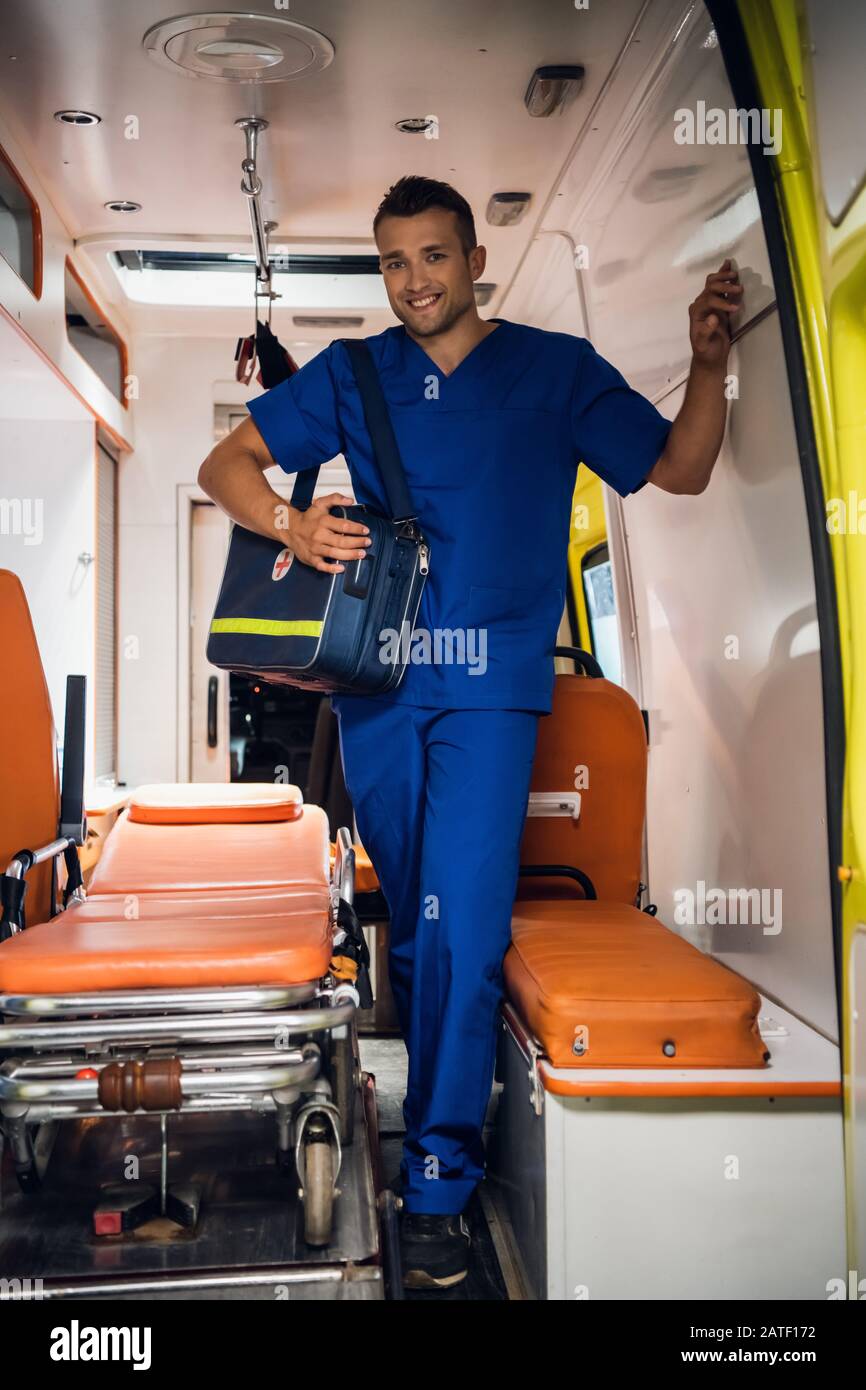Young man in blue medical uniform with medical bag in the ambulance car ...