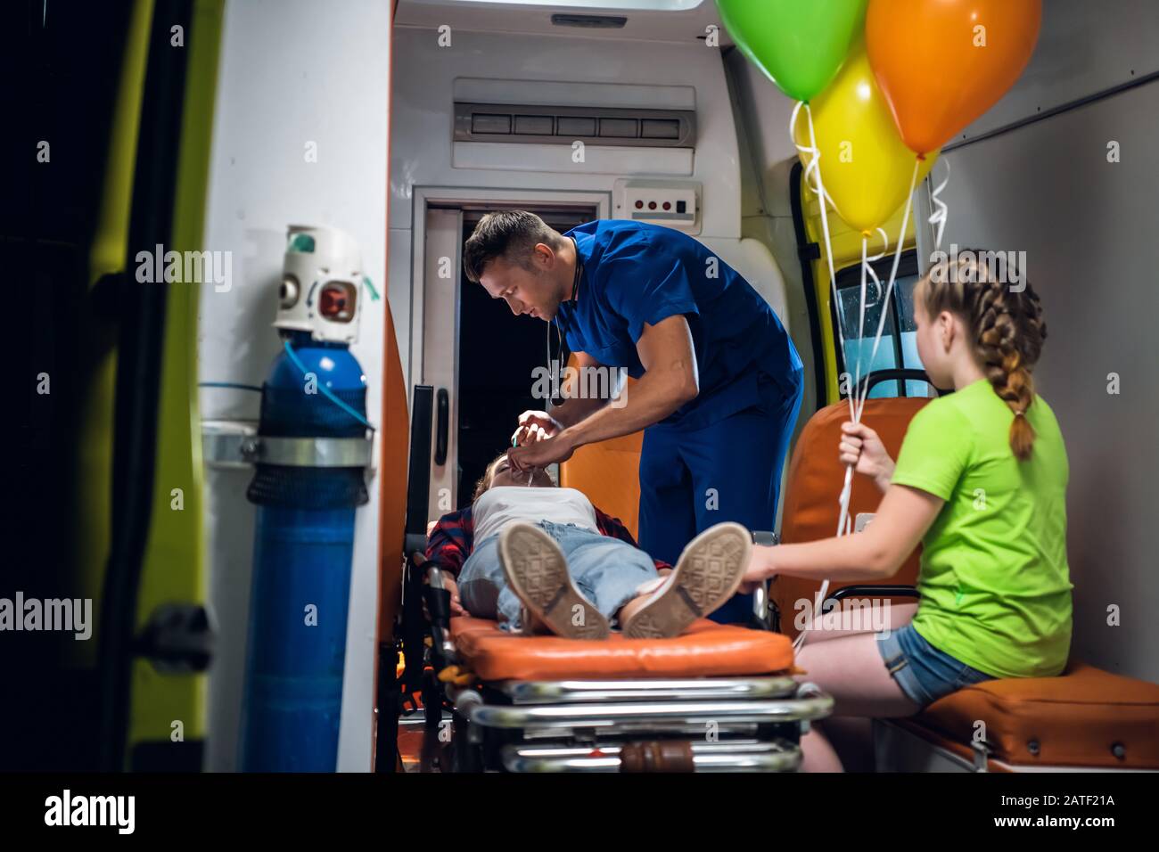 Ambulance car, parademic in blue medical uniform puts oxygen mask on ...