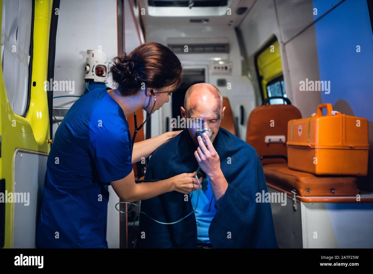Young Nurse In Uniform Puts Her Hand On Man Who Sits In Oxygen Mask In