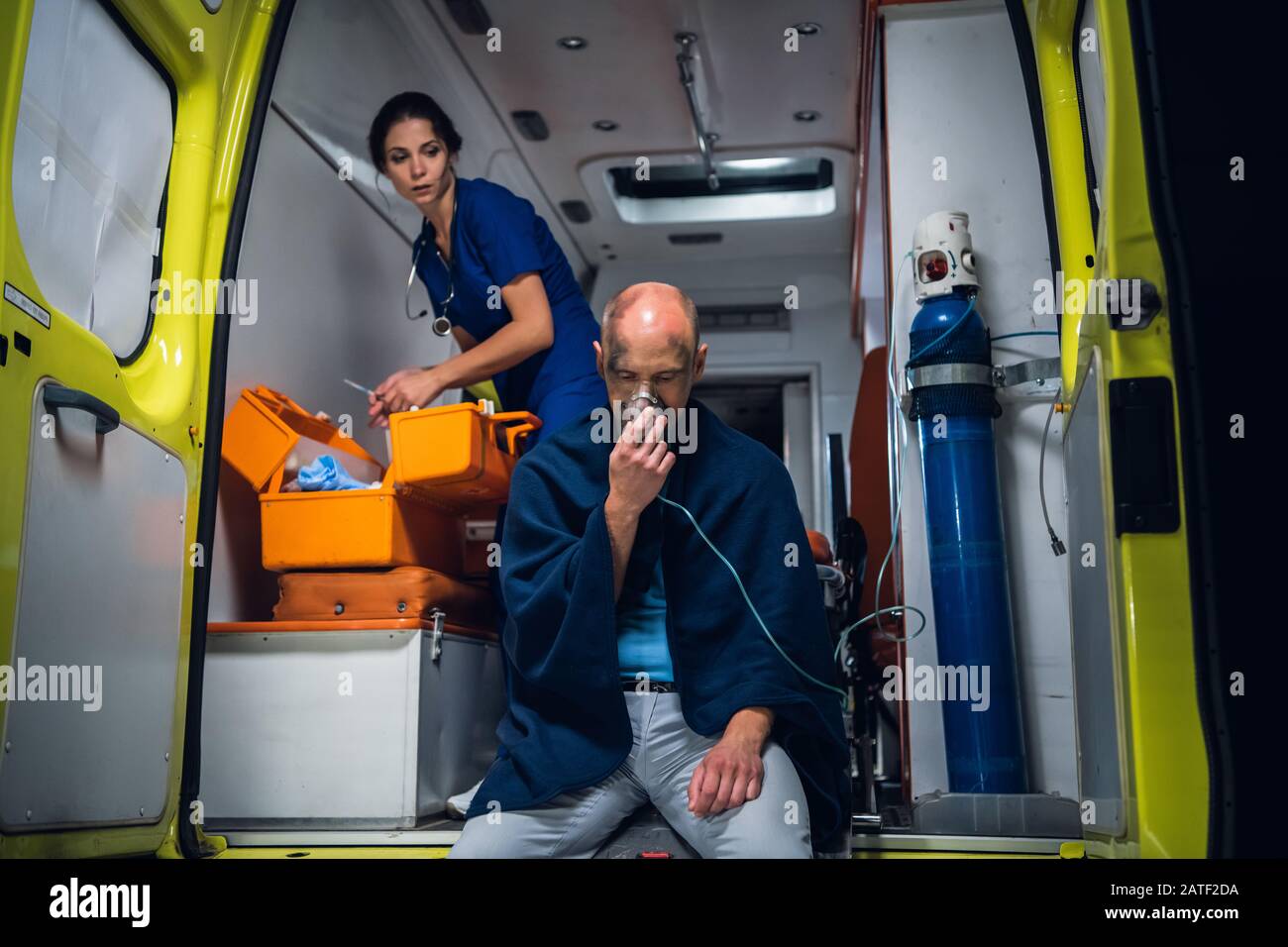 Man breathe through oxygen mask, young nurse in medical uniform packs ...