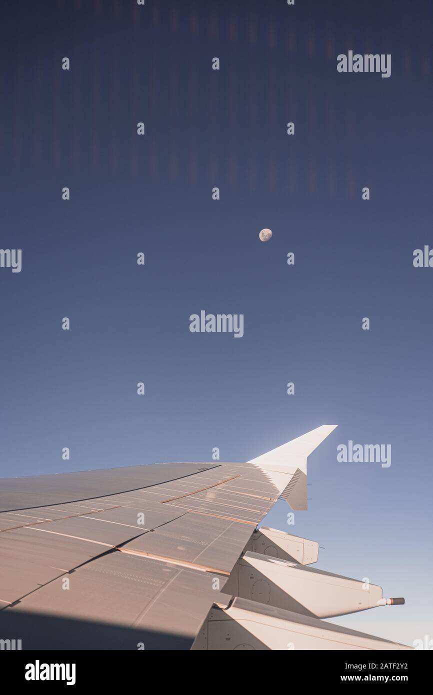 airplane wing through the airplane window with the moon in the ...