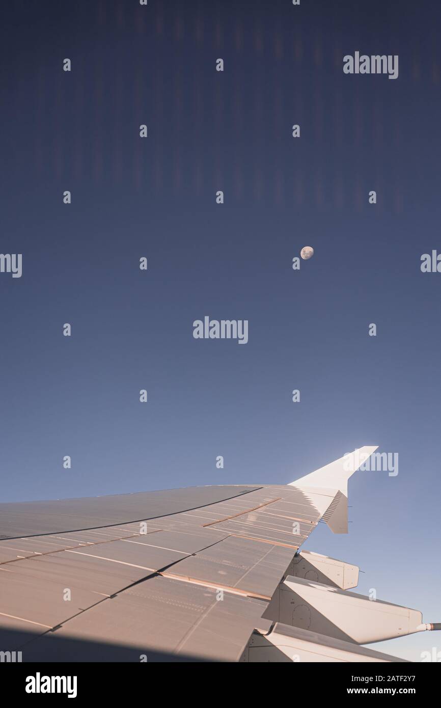 airplane wing through the airplane window with the moon in the ...