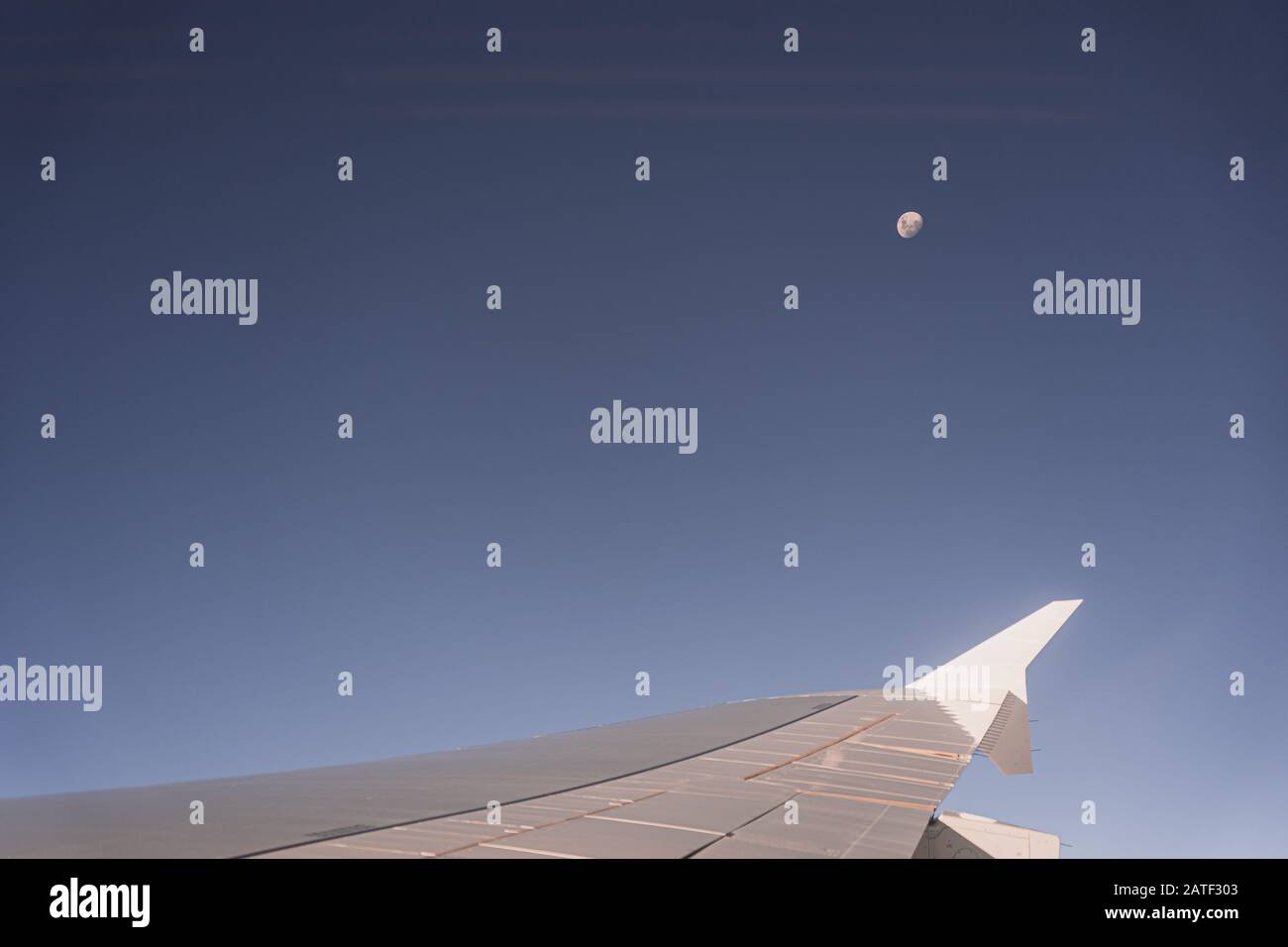 airplane wing through the airplane window with the moon in the ...
