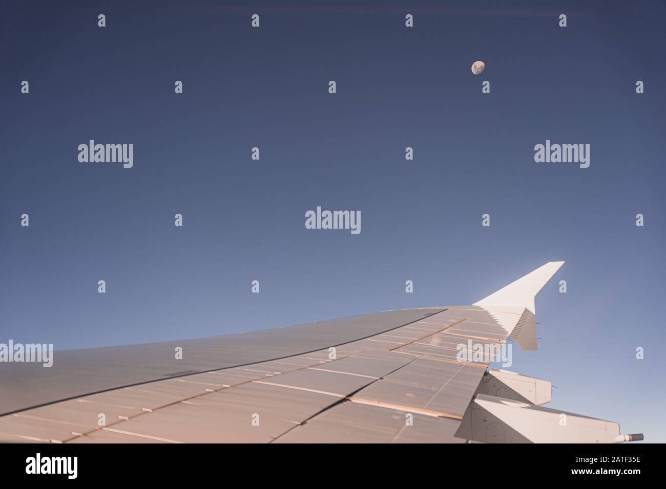 airplane wing through the airplane window with the moon in the ...