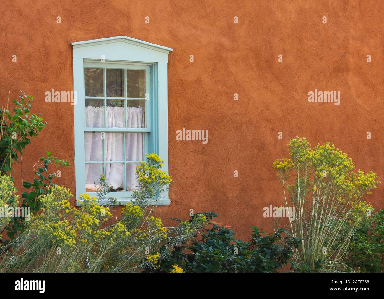 Blue wooden window in terracotta walled building. Pueblo adobe plaster ...