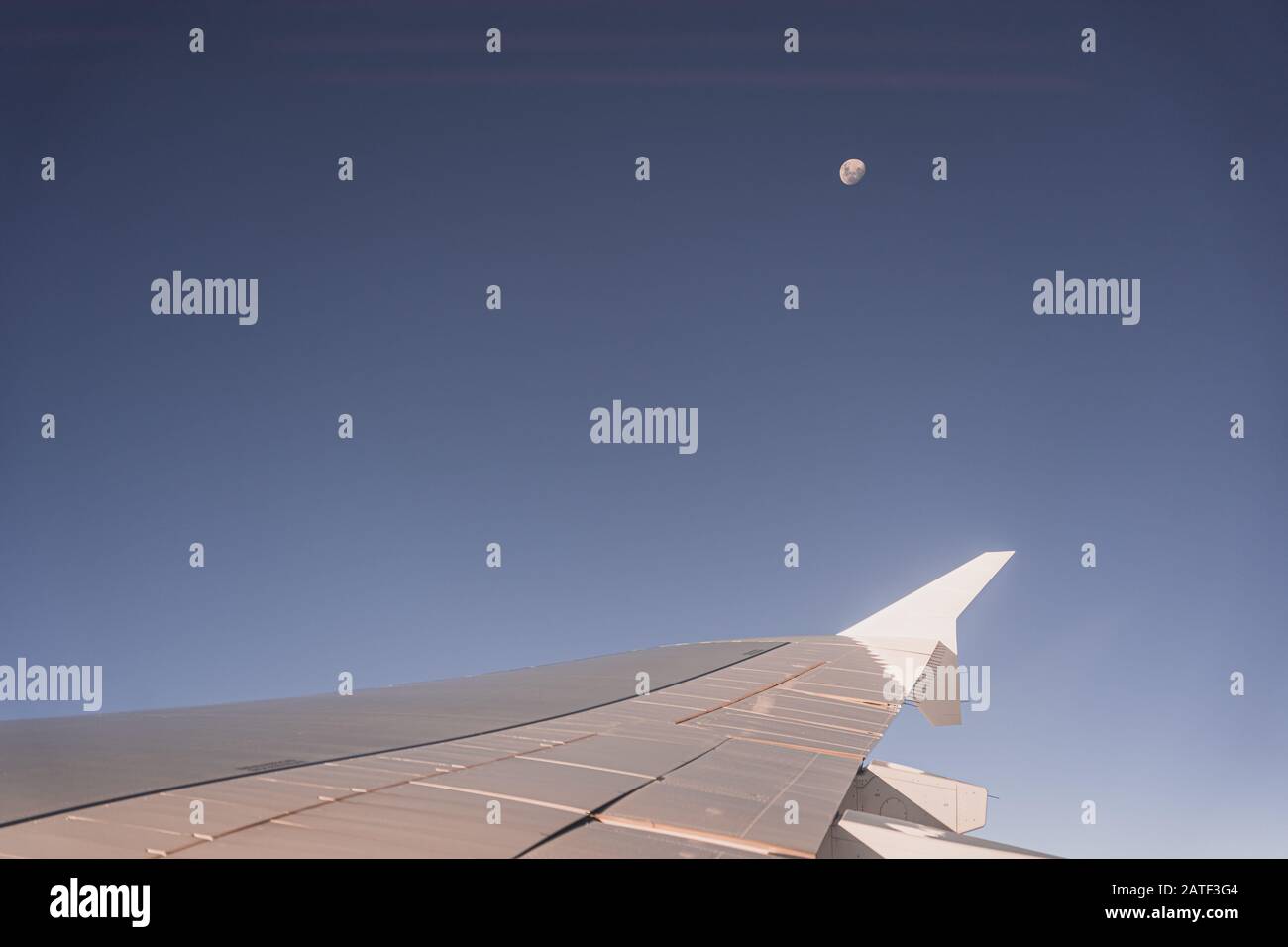 airplane wing through the airplane window with the moon in the ...
