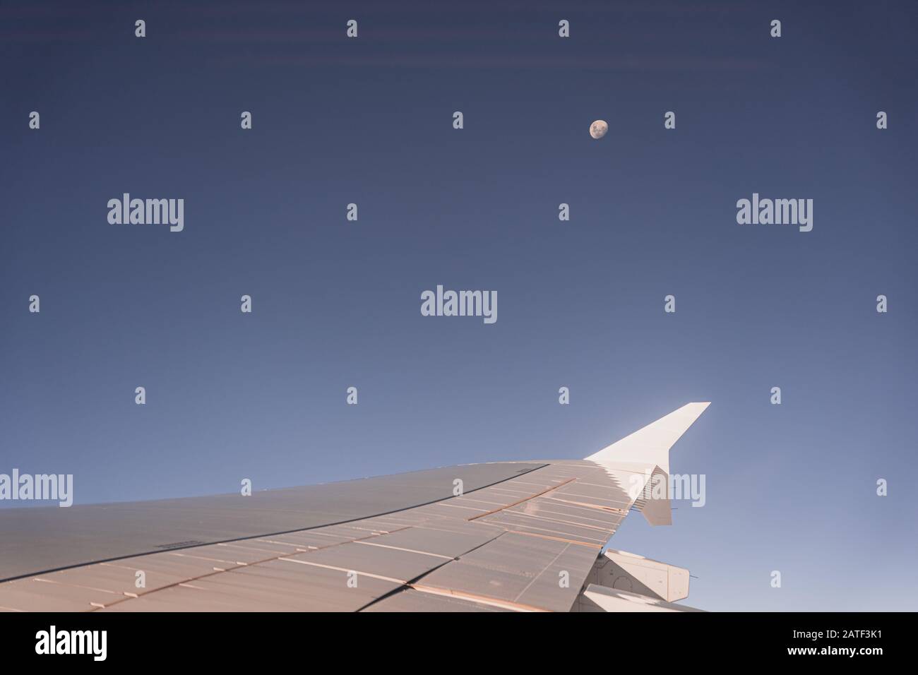 airplane wing through the airplane window with the moon in the ...