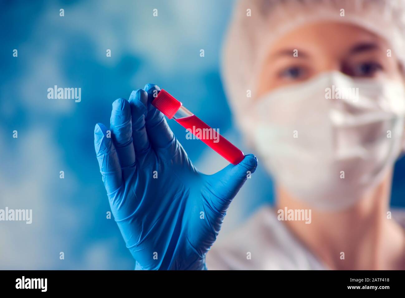 Doctor in medical mask and blue gloves holding tube with blood test ...