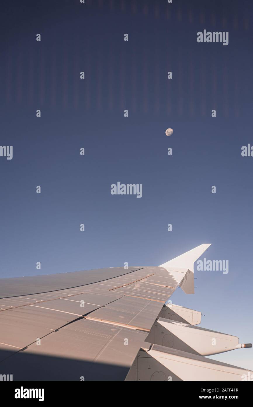 airplane wing through the airplane window with the moon in the ...