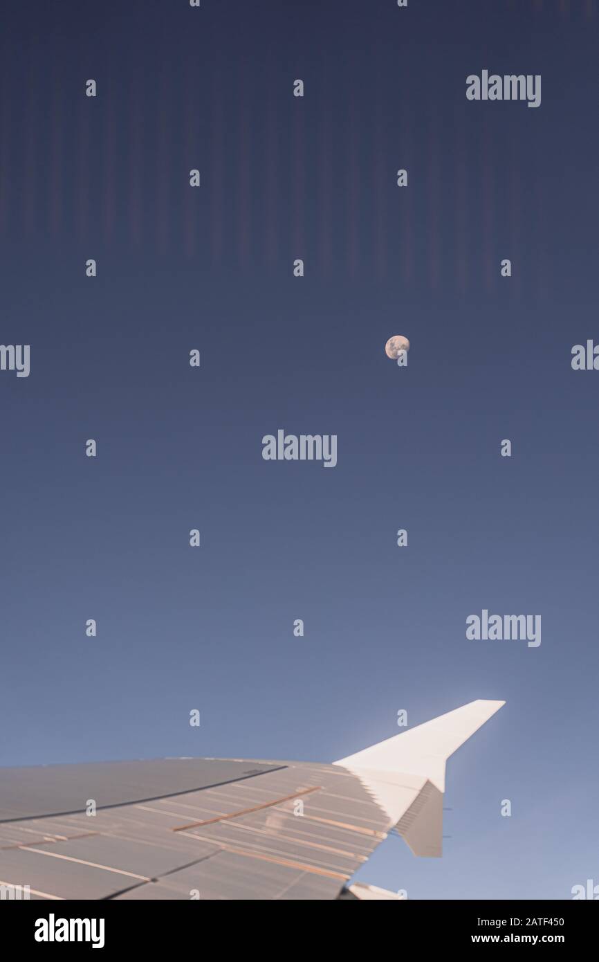 airplane wing through the airplane window with the moon in the ...