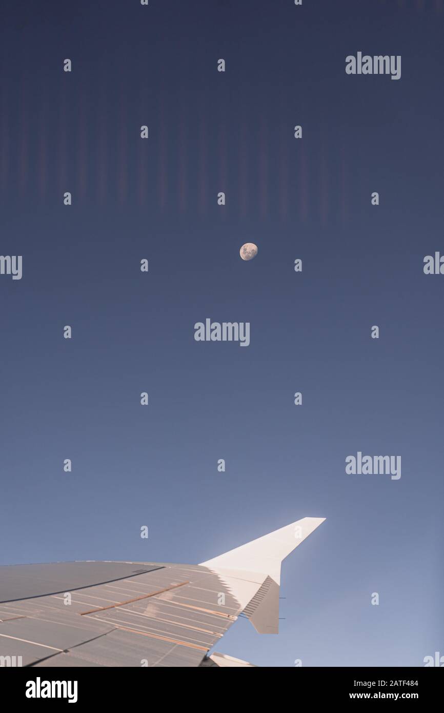 airplane wing through the airplane window with the moon in the ...