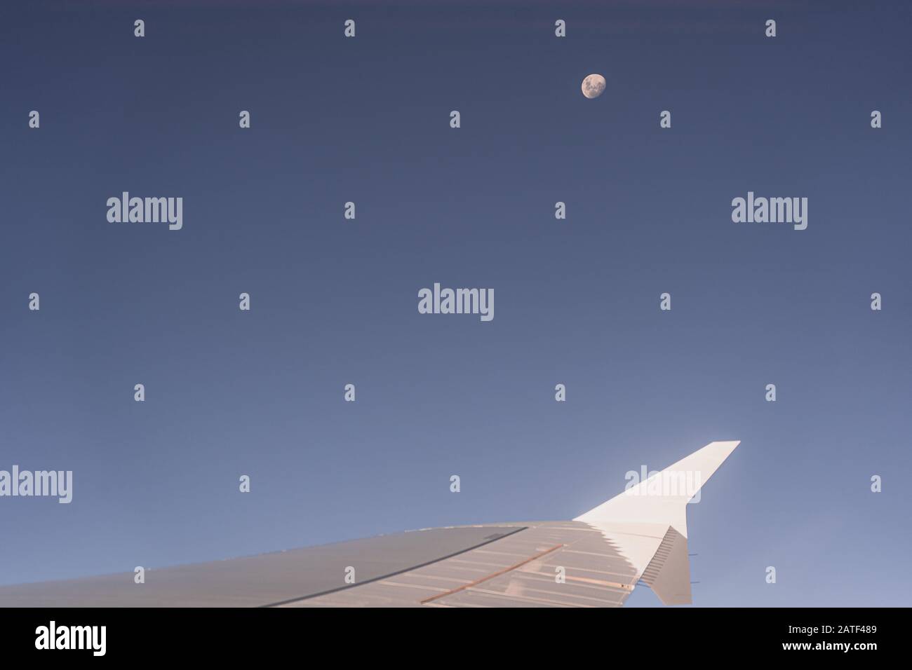 airplane wing through the airplane window with the moon in the ...