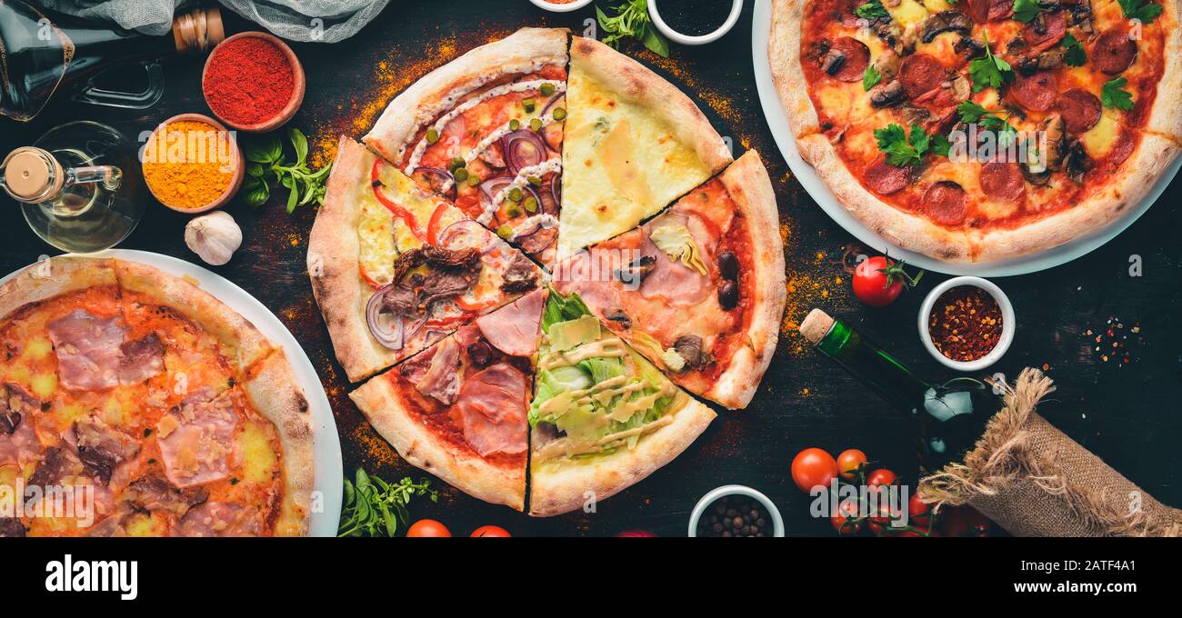 A set of Italian pizza. Italian cuisine. On a black wooden background ...