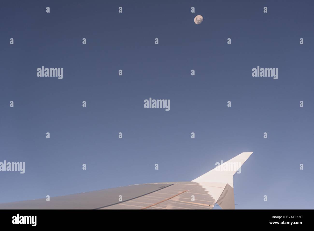 airplane wing through the airplane window with the moon in the ...