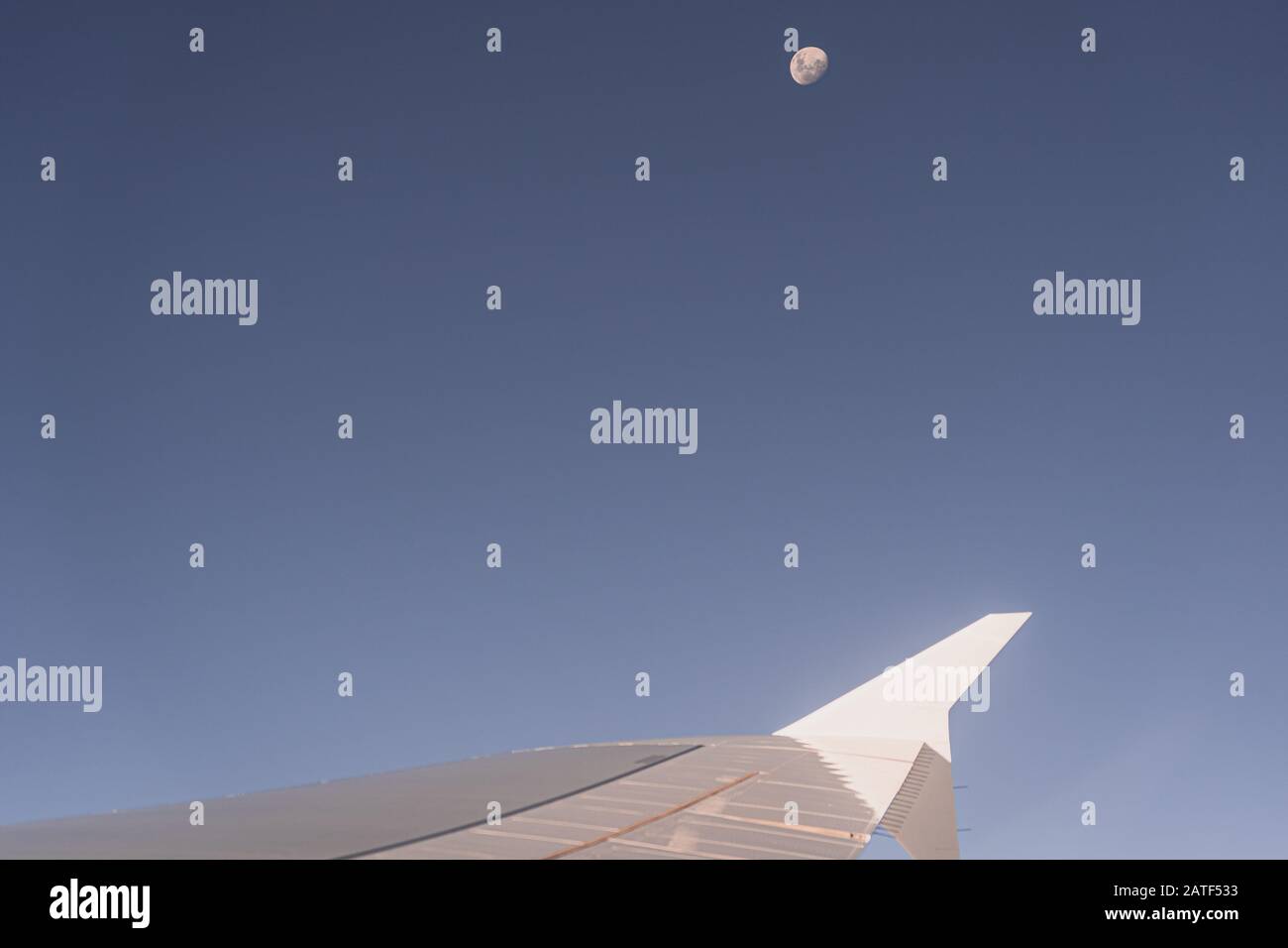 airplane wing through the airplane window with the moon in the ...