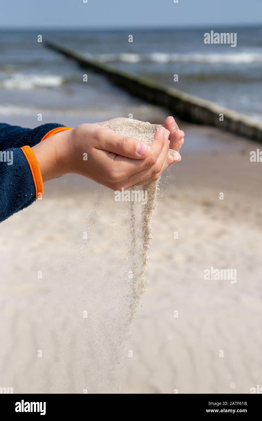 a little boy slowly lets sand flow through his hands scattered by the ...