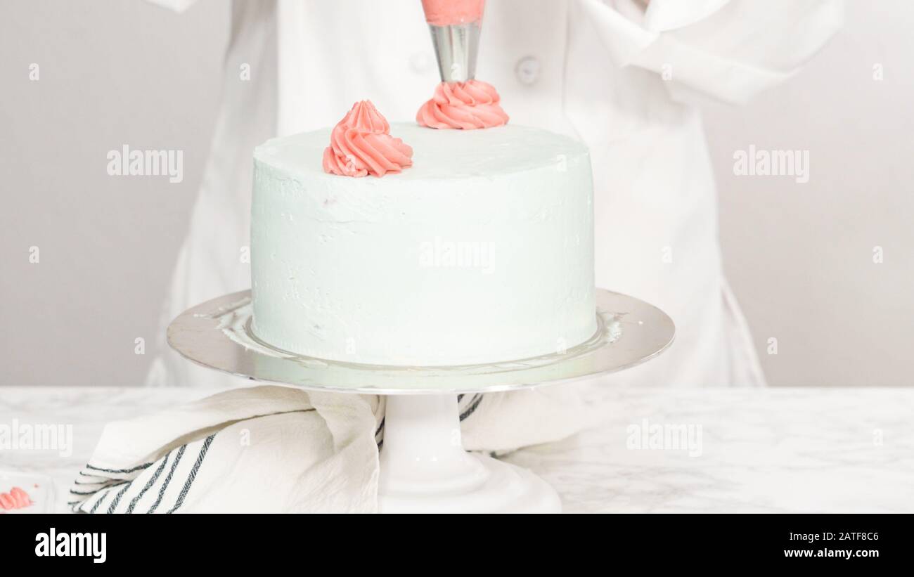 Piping buttercream rosettes on top of round three-layer vanilla cake ...