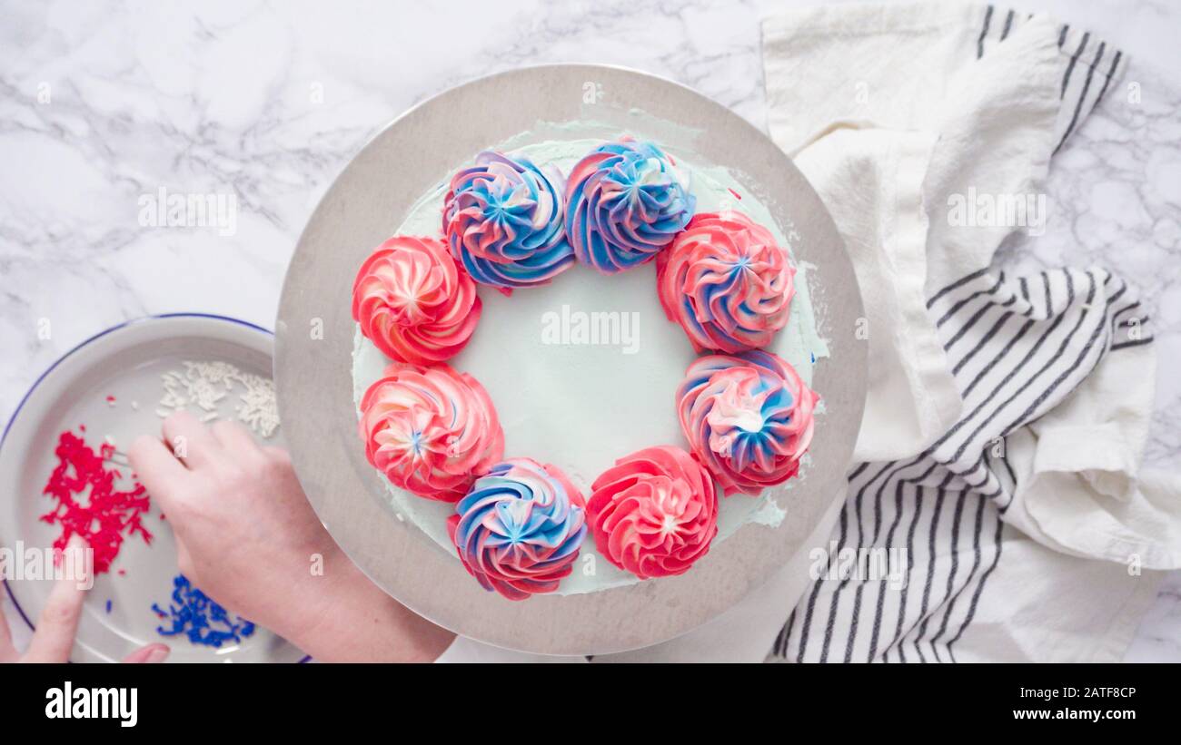 Piping buttercream rosettes on top of round three-layer vanilla cake ...