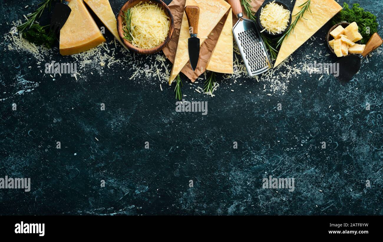 Parmesan. Pieces of Parmesan cheese on black stone background. Top view ...