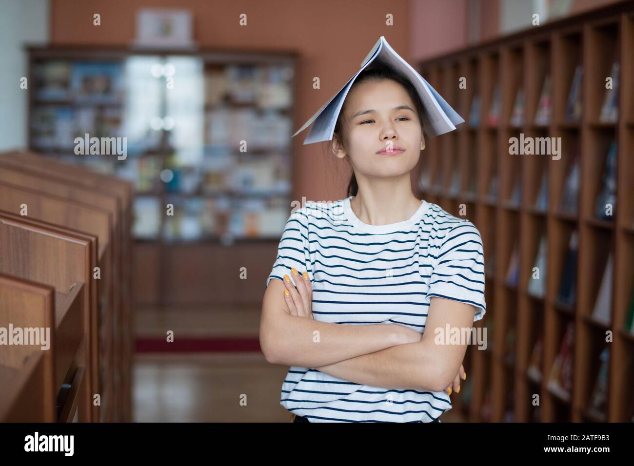 Clever college student with her arms crossed by chest and copybook on ...